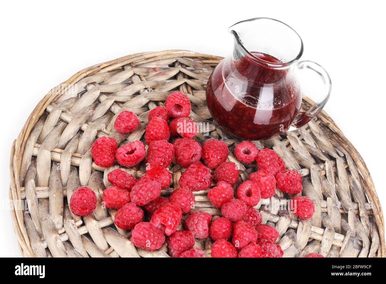 Raspberries and jug with jam on wicker mat isolated on white Stock ...