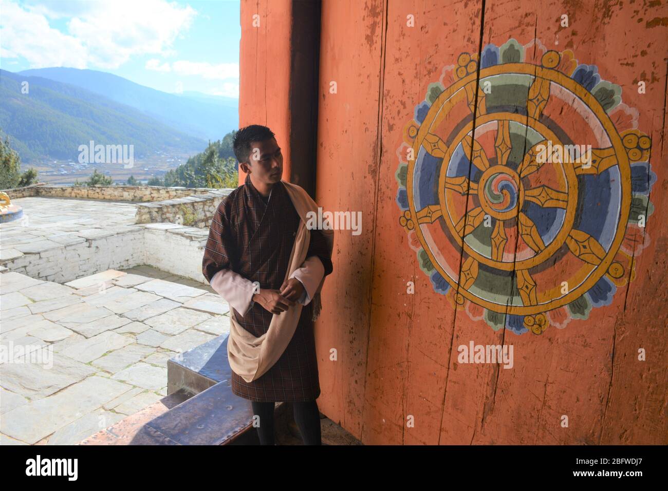 A tour guide beside a 'wheel of life' at Jakar Dzong, Bumthang District ...