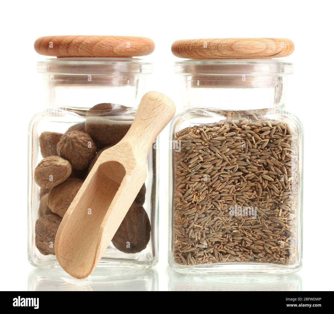 jars and wooden spoon with nutmeg and cumin isolated on white Stock ...