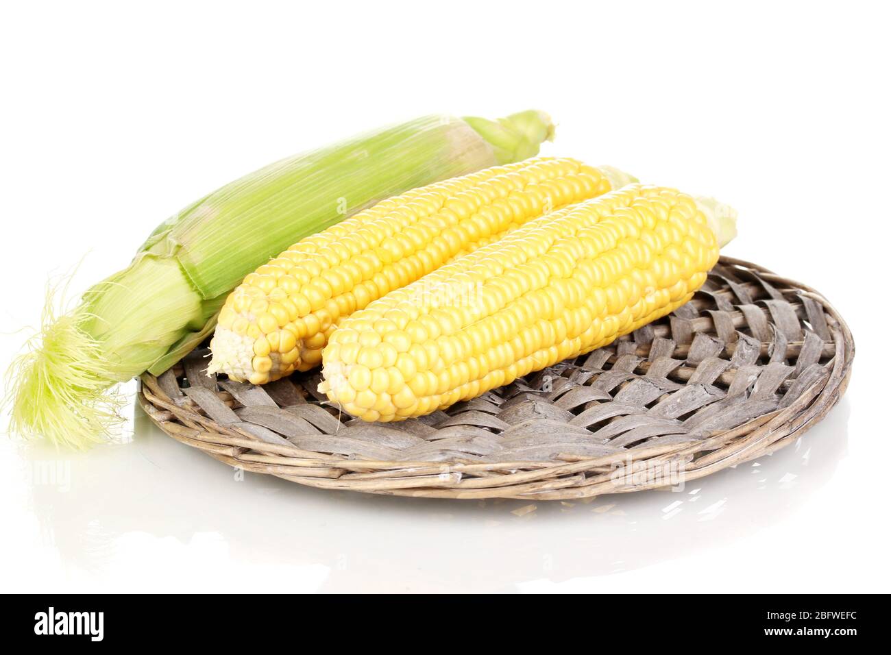 Fresh corn cobs on wicker mat isolated on white Stock Photo - Alamy