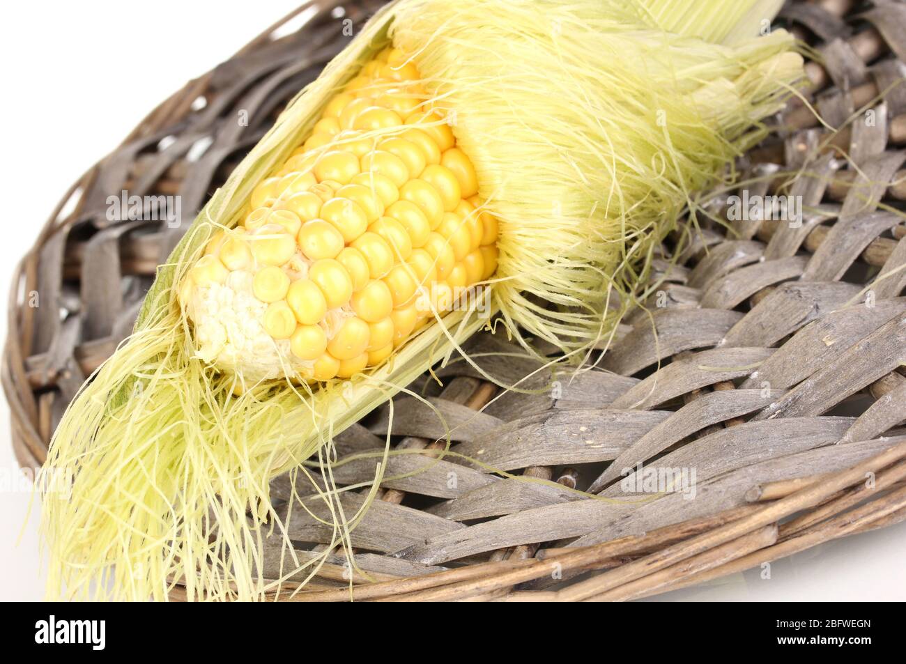 Fresh corn cob on wicker mat isolated on white Stock Photo - Alamy
