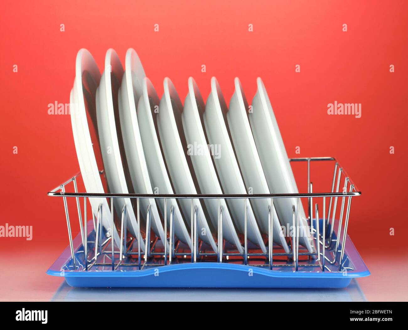 clean dishes on stand on red background Stock Photo - Alamy