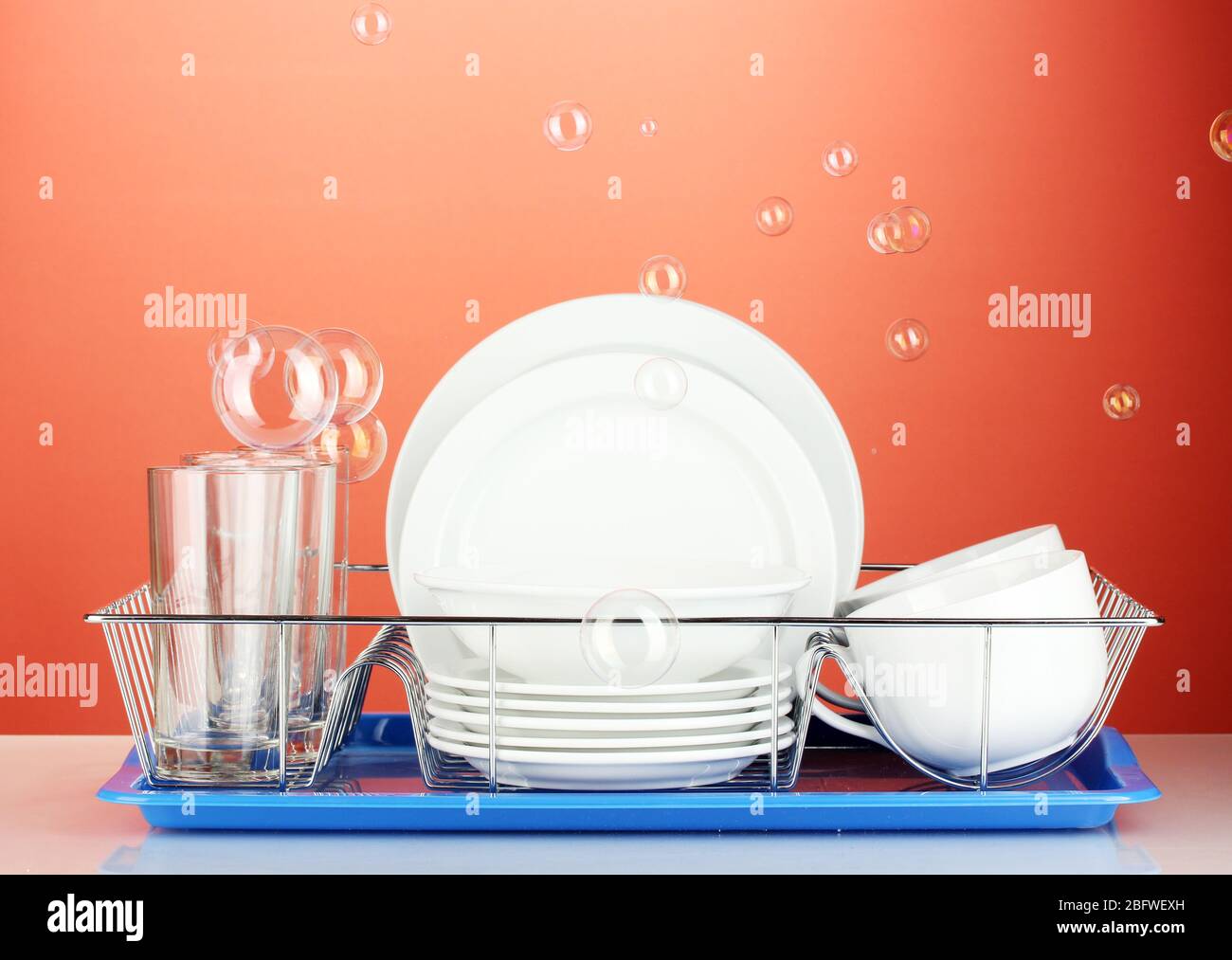 clean dishes on stand on red background Stock Photo - Alamy