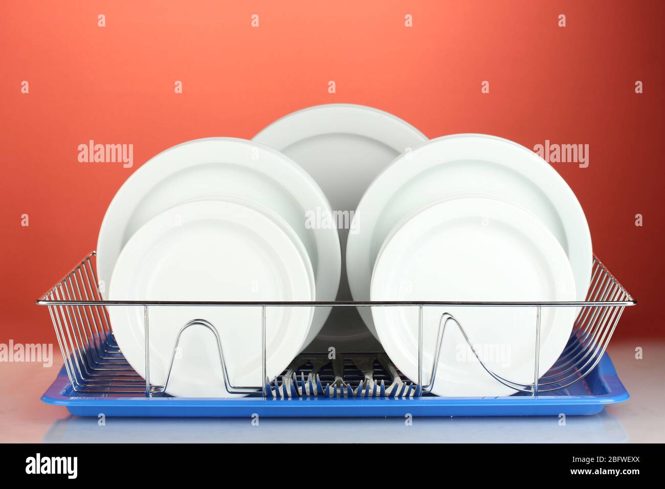 clean dishes on stand on red background Stock Photo - Alamy