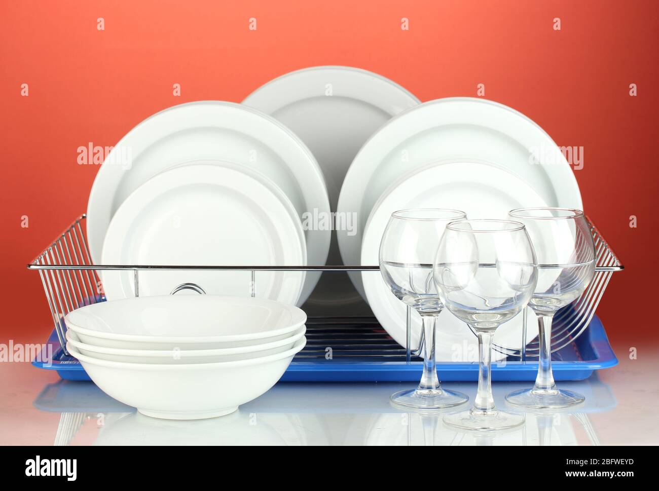 clean dishes on stand on red background Stock Photo - Alamy