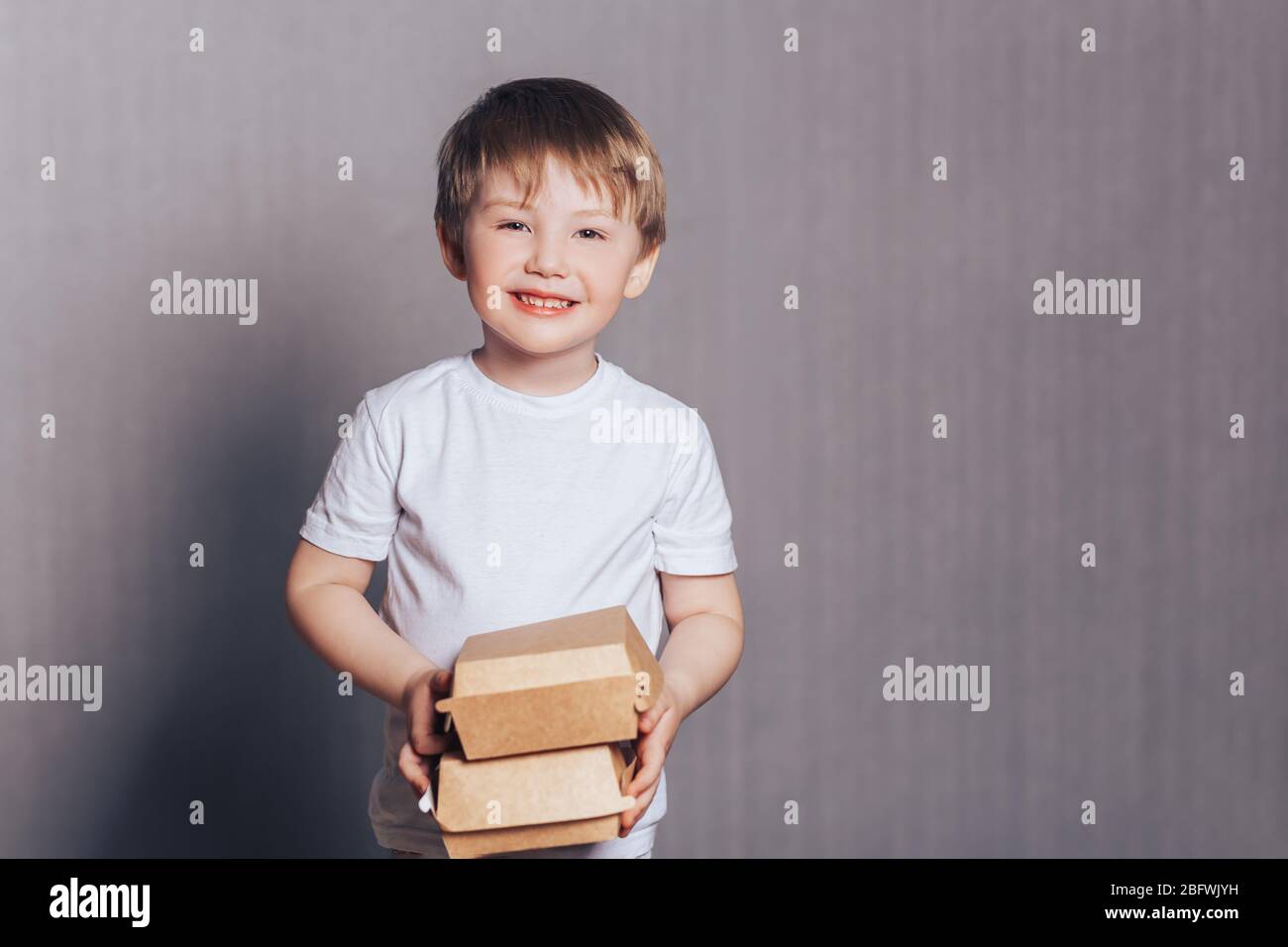 Beautiful little boy holding boxes in hands Stock Photo - Alamy