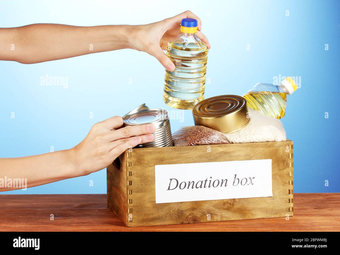 Donation box with food on blue background close-up Stock Photo - Alamy