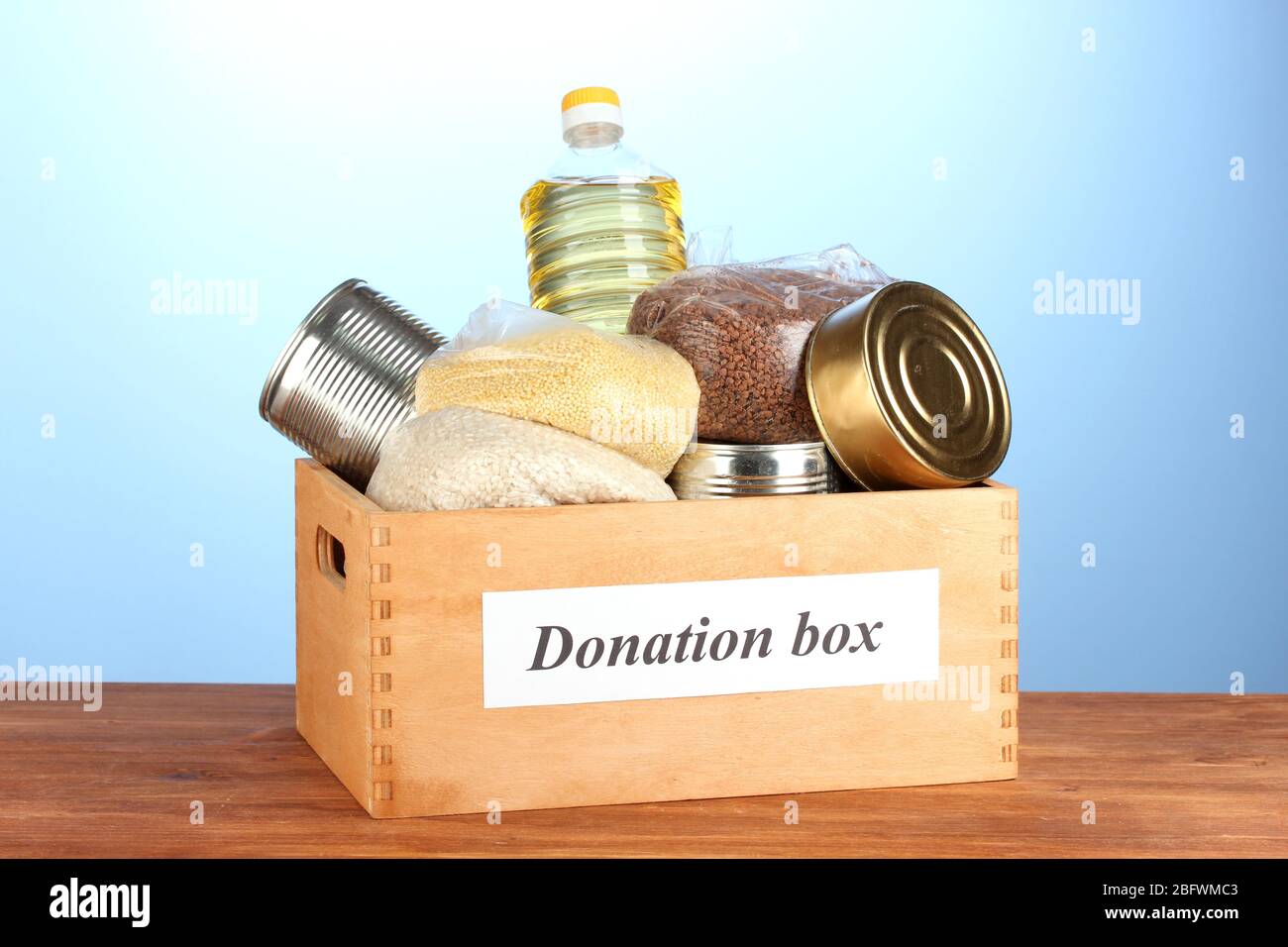 Donation box with food on blue background close-up Stock Photo - Alamy
