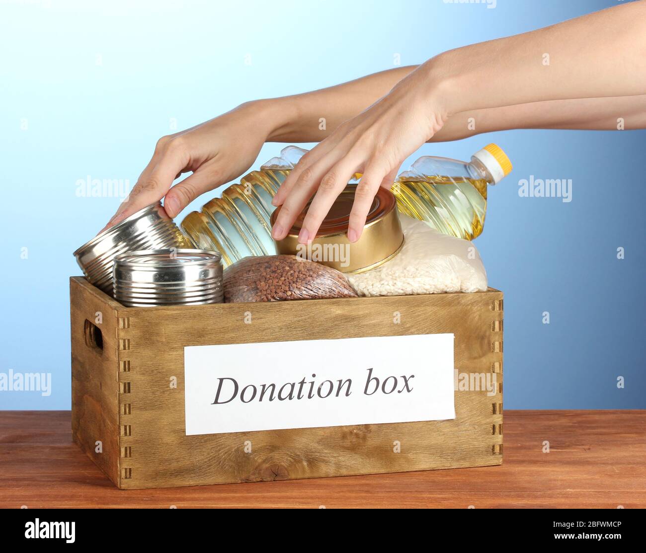 Donation box with food on blue background close-up Stock Photo - Alamy