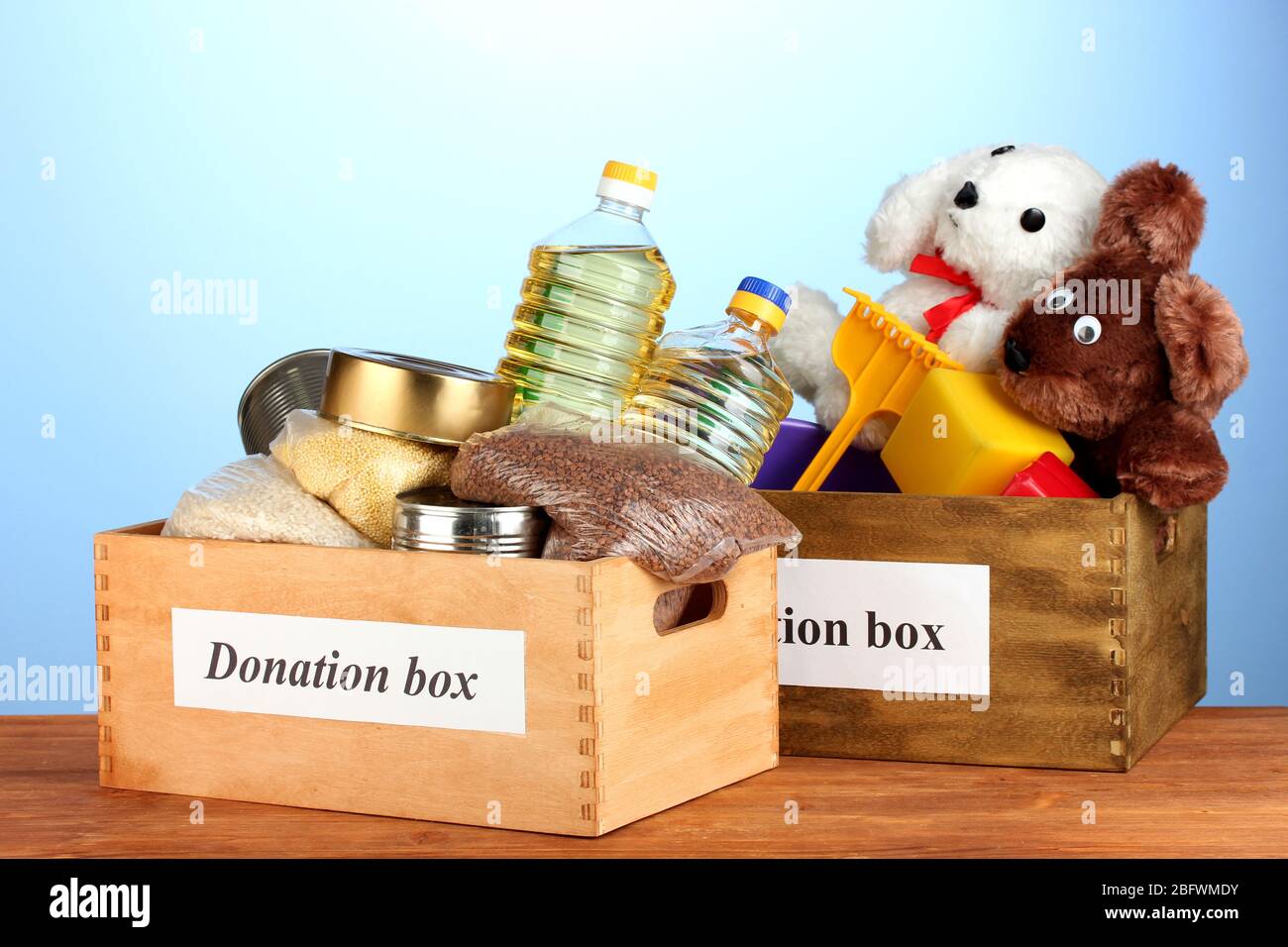 Donation box with food and children's toys on blue background close-up ...