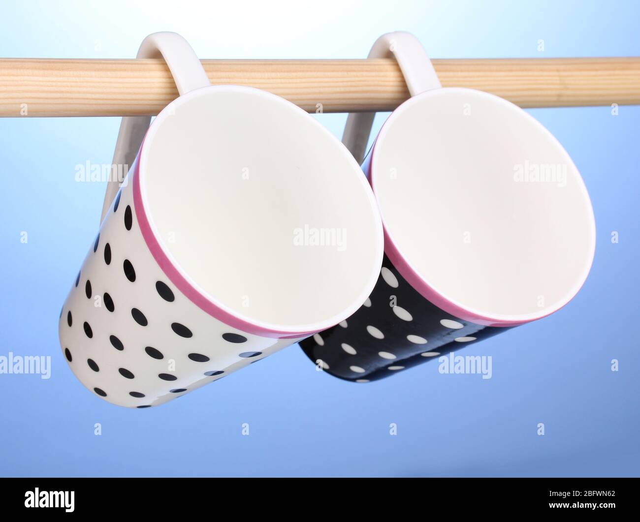 Nice cups hanging on stick on blue background Stock Photo - Alamy