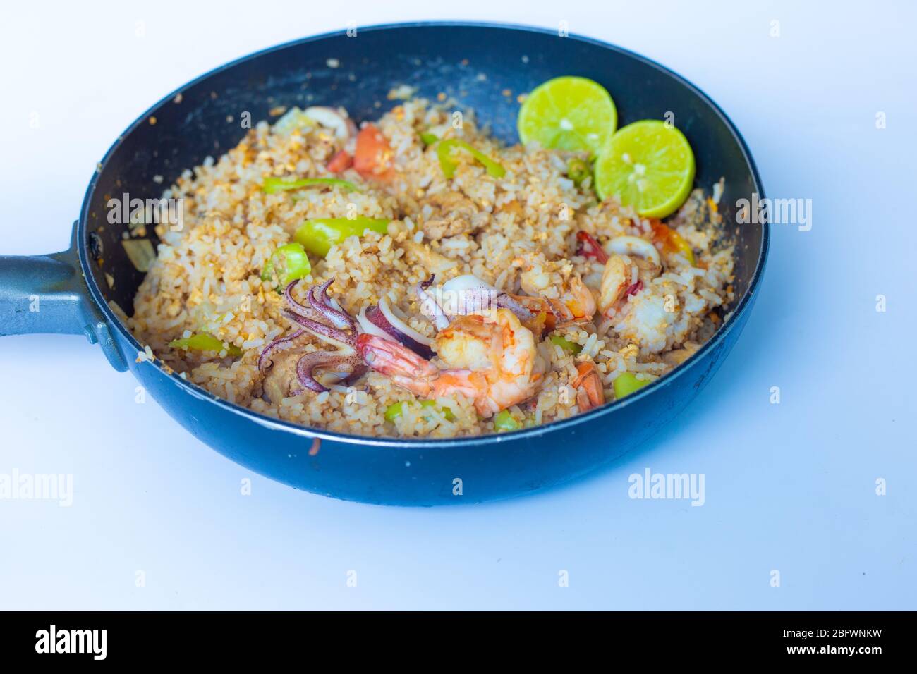 Asian fried rice with tiger prawn shrimp and seafood in pan on white ...