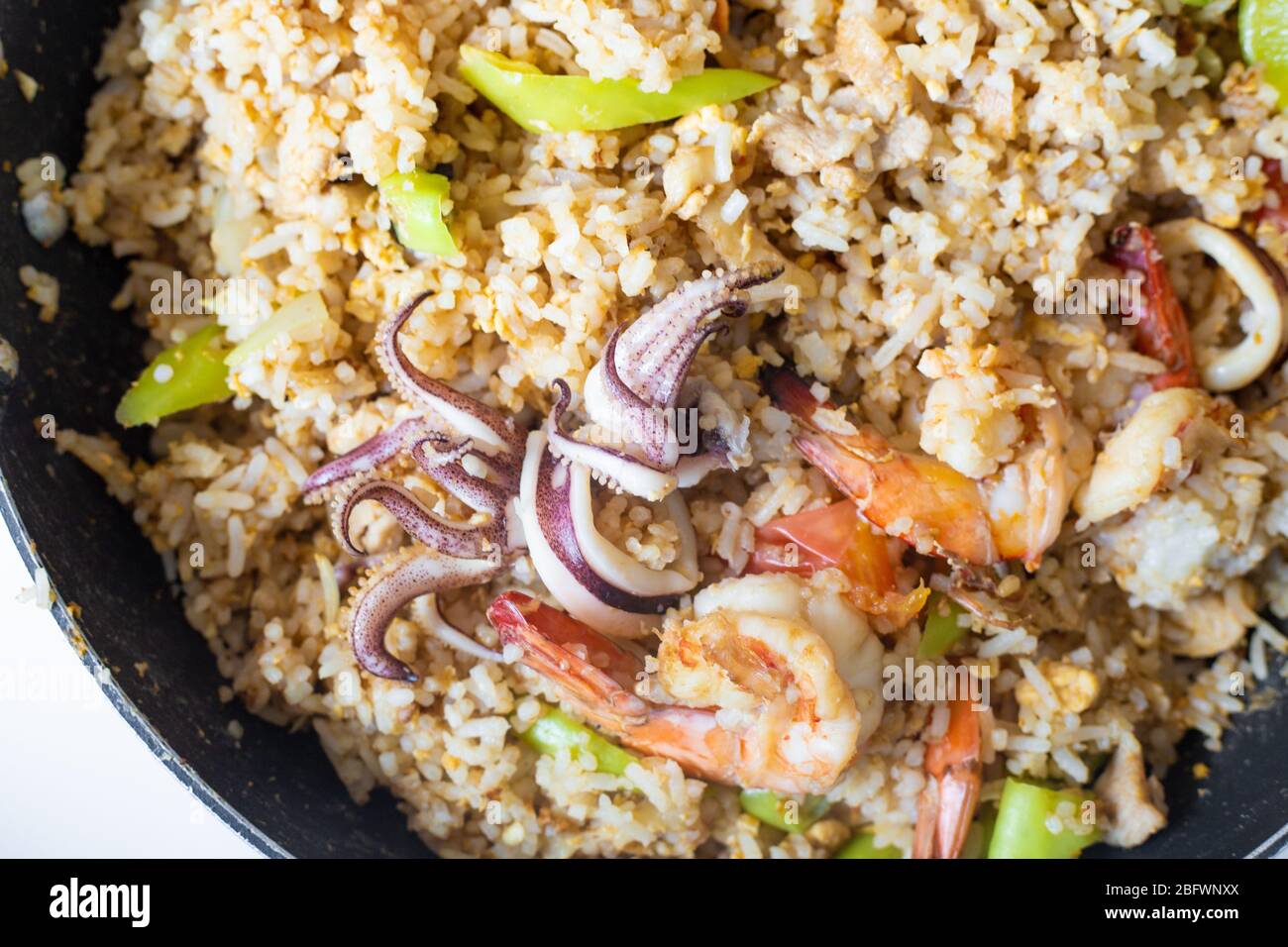 Asian fried rice with tiger prawn shrimp and seafood in pan on white ...