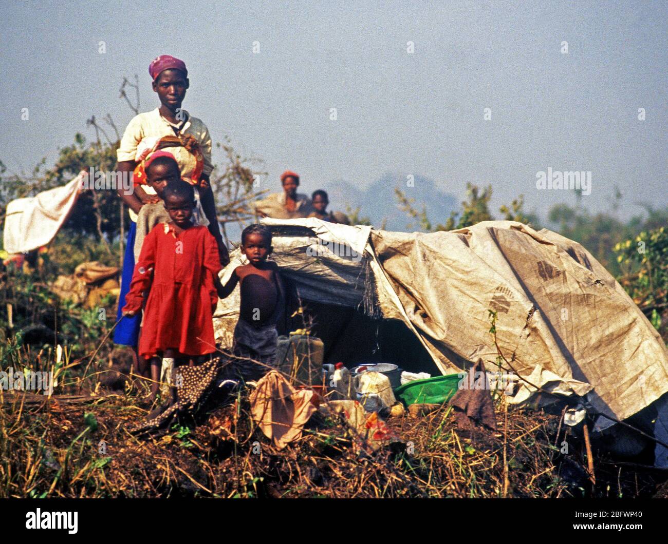 1994 - A Rwandan family pose in front of their makeshift home. The ...