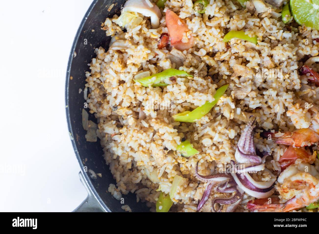 Asian fried rice with tiger prawn shrimp and seafood in pan on white ...