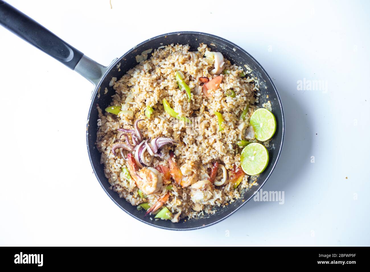 Asian fried rice with tiger prawn shrimp and seafood in pan on white ...