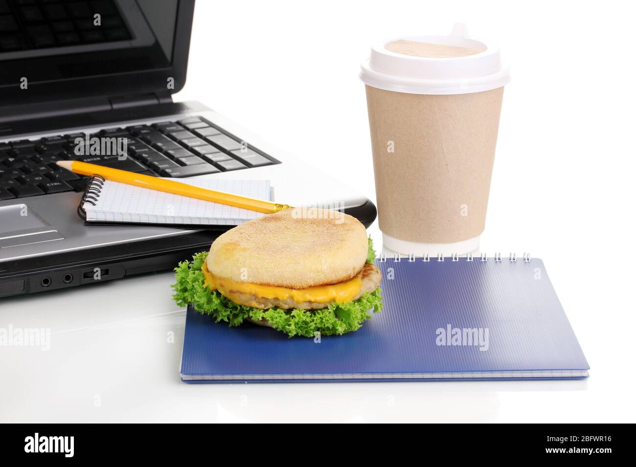 Eating at work place near laptop Stock Photo - Alamy
