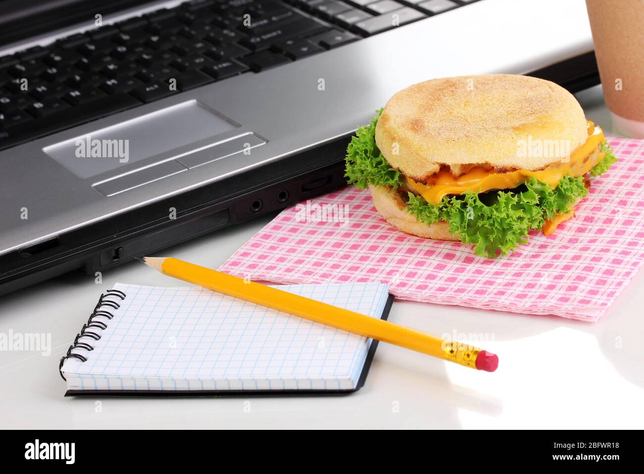 Eating at work place near laptop Stock Photo - Alamy