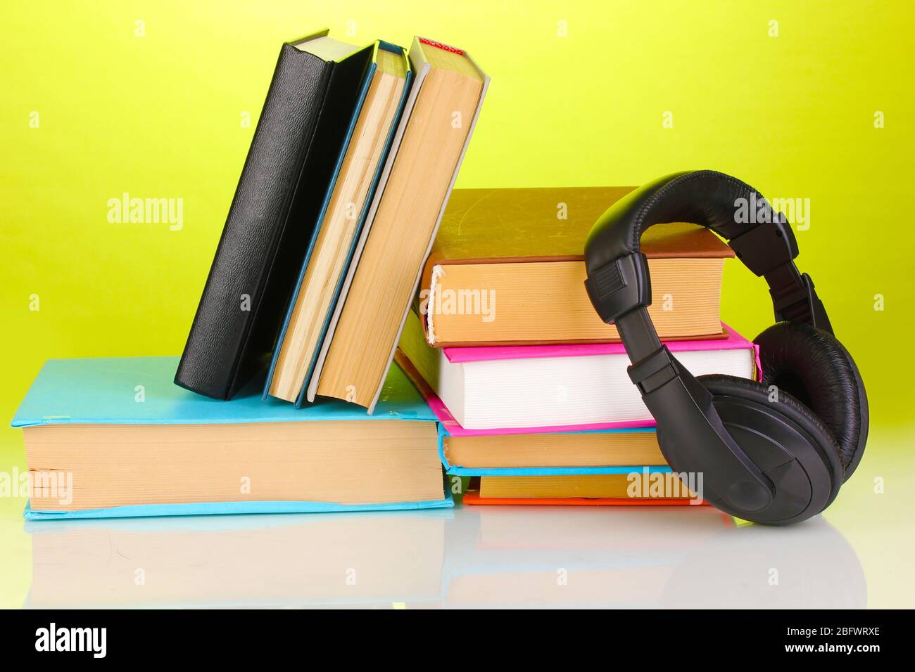Headphones on books on green background Stock Photo - Alamy