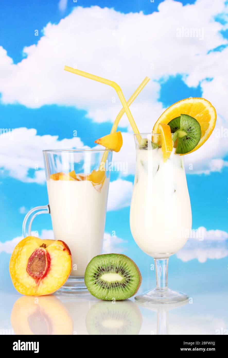 Delicious milk shake with fruit on table on sky background Stock Photo ...