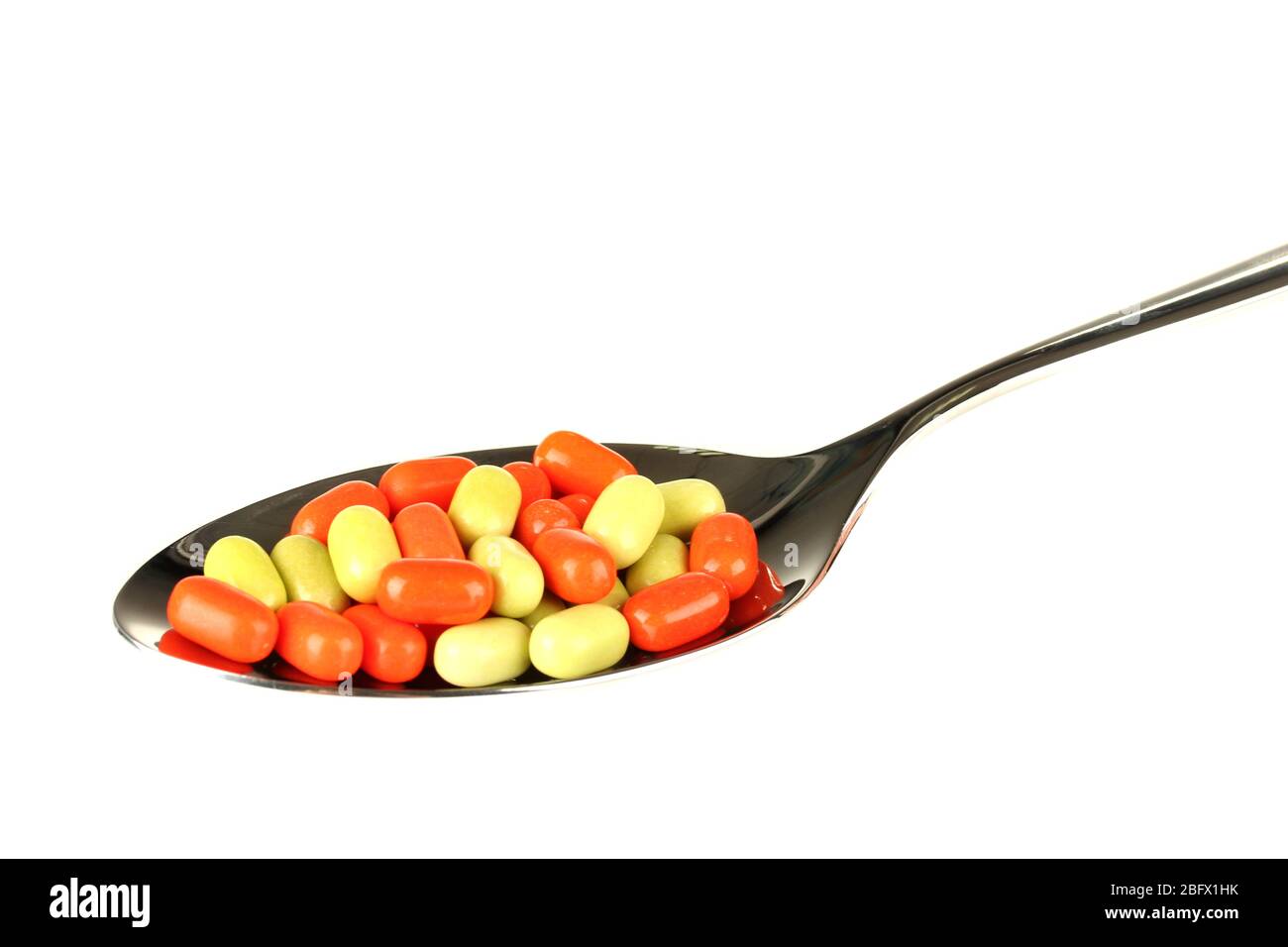 colorful pills on spoon on white background close-up Stock Photo - Alamy