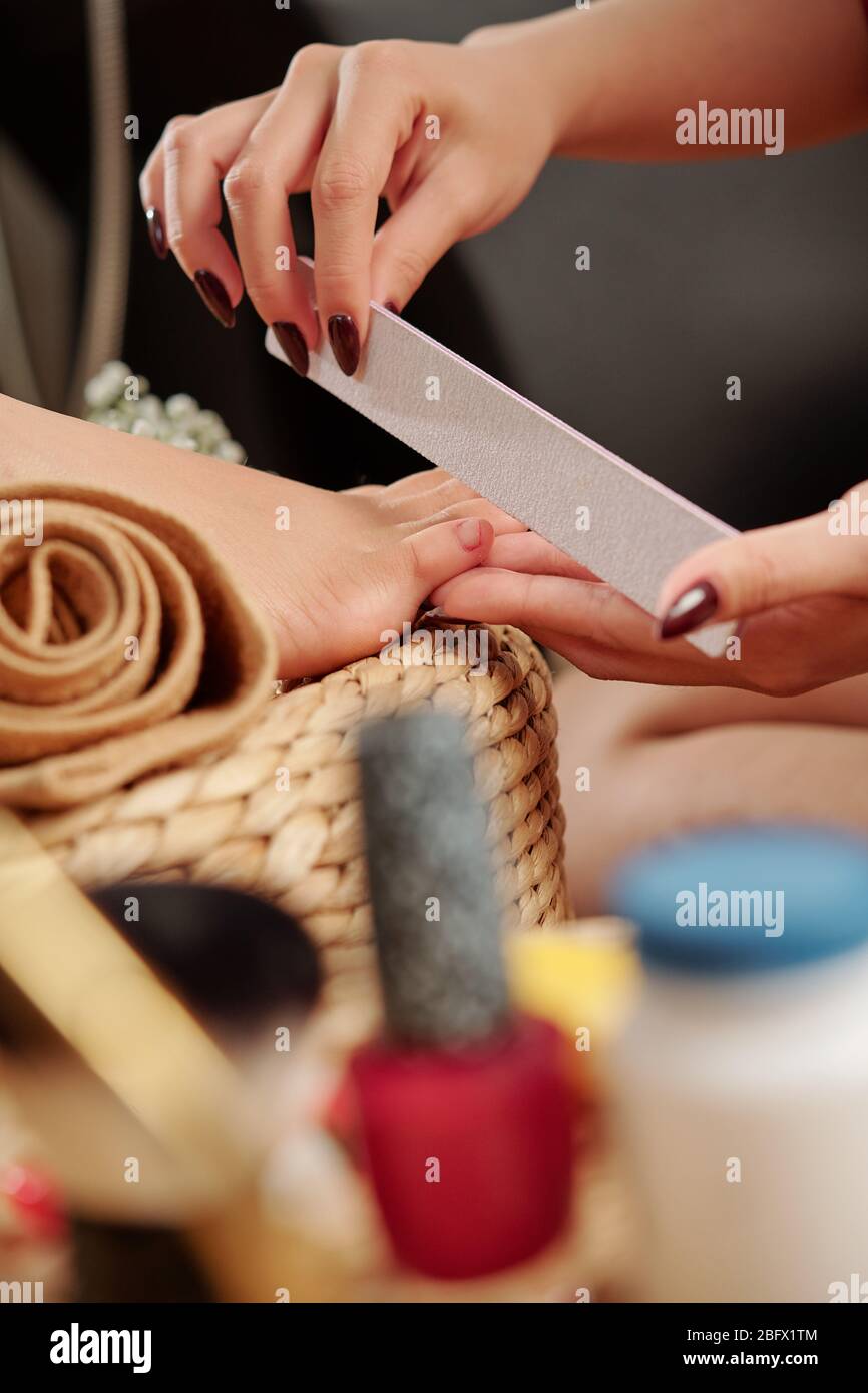Pedicurist filing toenails of female clients in spa salon Stock Photo ...