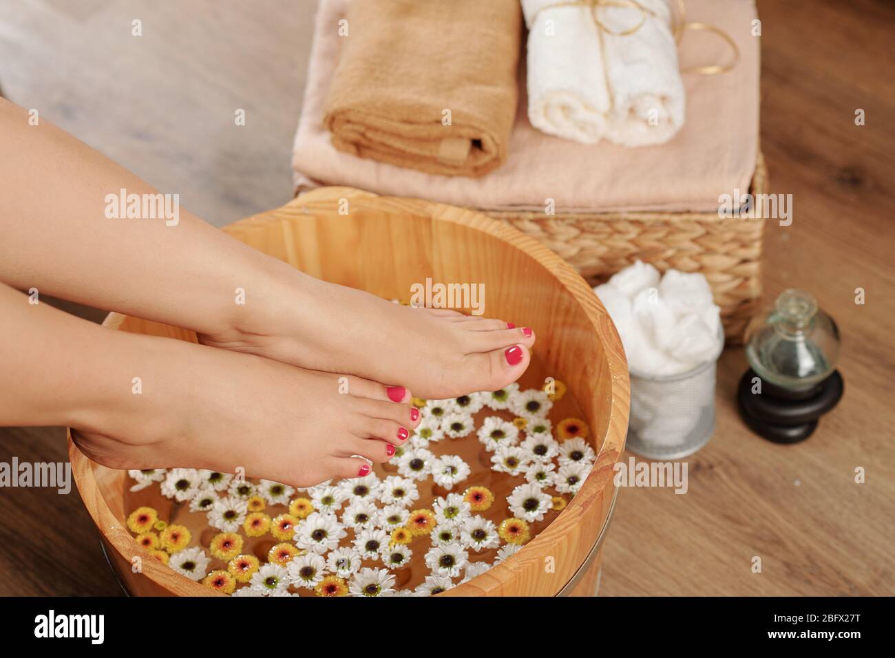 Woman putting feet in basin with flower infused warm water to soak it ...