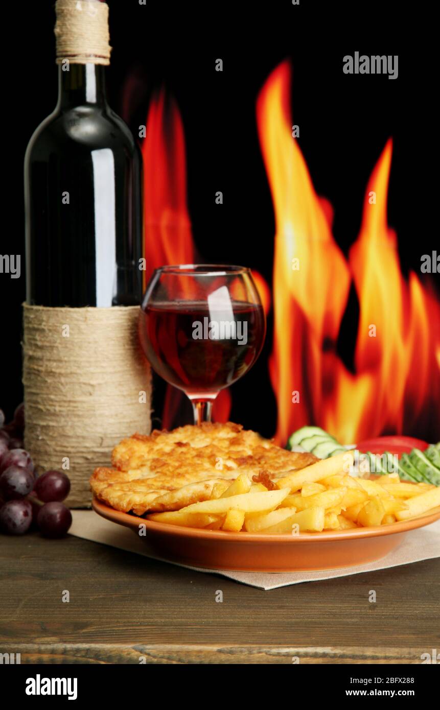 Roast chicken cutlet with french fries, glass of wine on fire ...