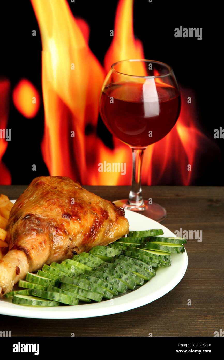 Roast chicken with french fries and cucumbers, glass of wine on wooden ...