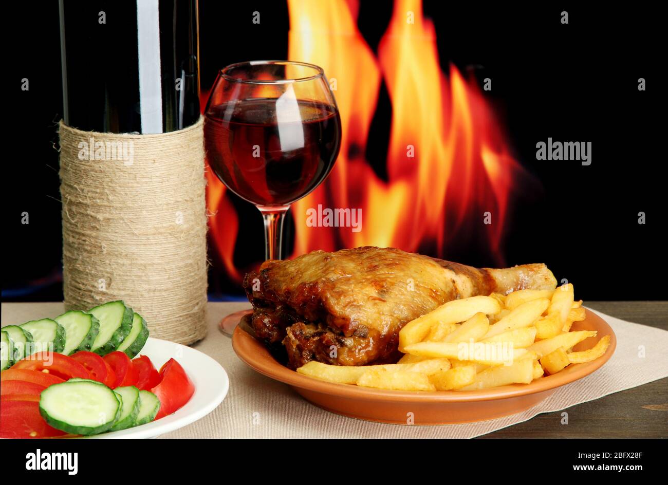 Roast chicken with french fries and cucumbers, glass of wine on wooden ...