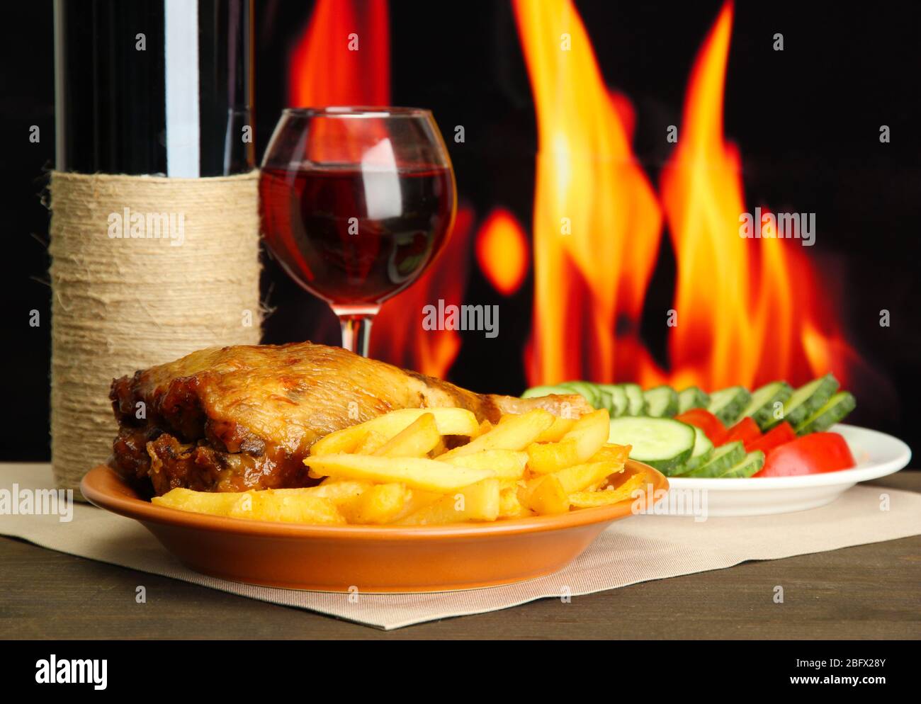 Roast chicken with french fries and cucumbers, glass of wine on wooden ...