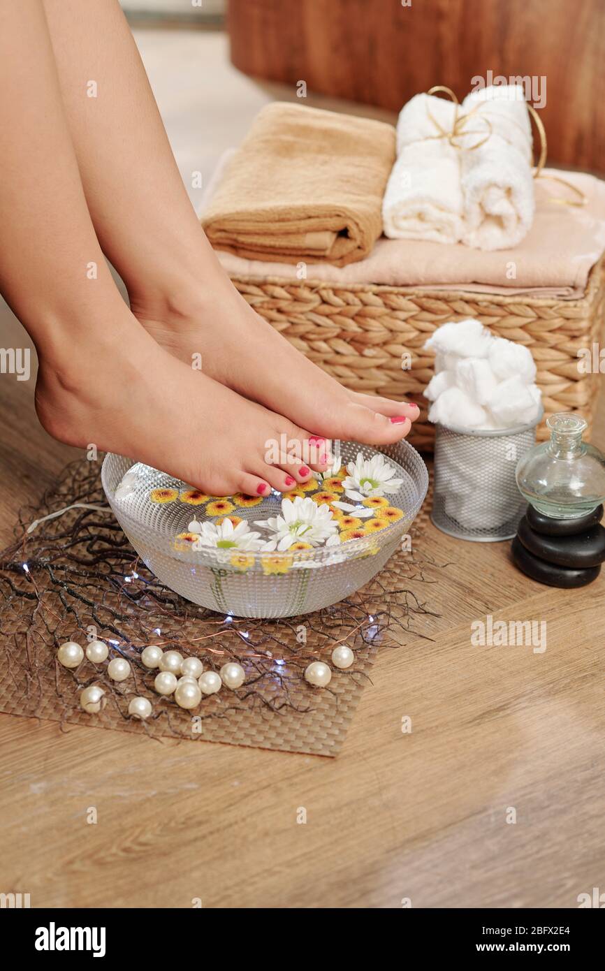 Pedicured feet of young woman over bowl with hot water, aroma oil and ...