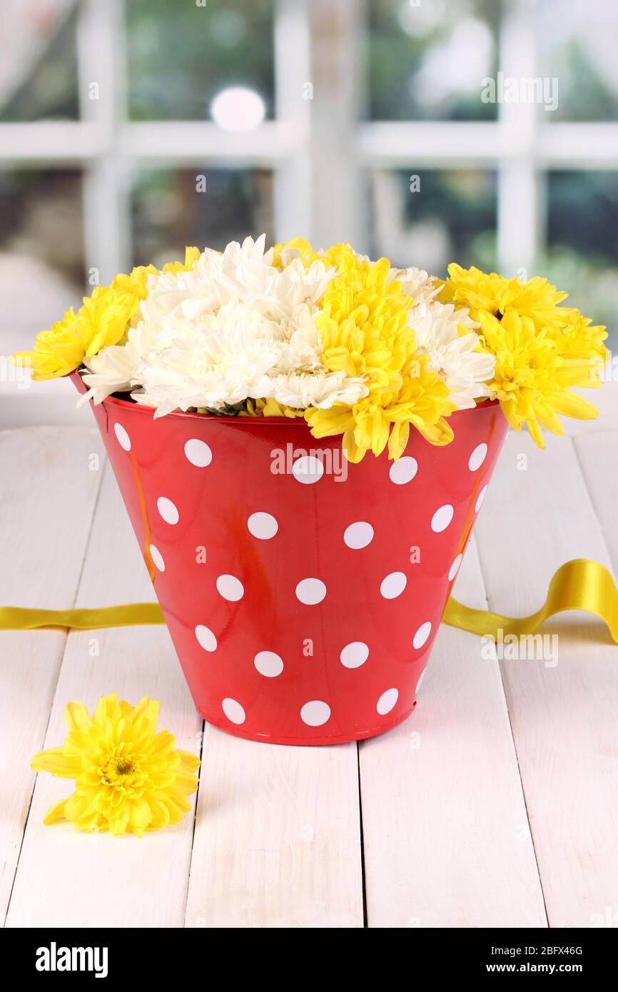 Red pail of peas with flowers on white wooden table on window ...