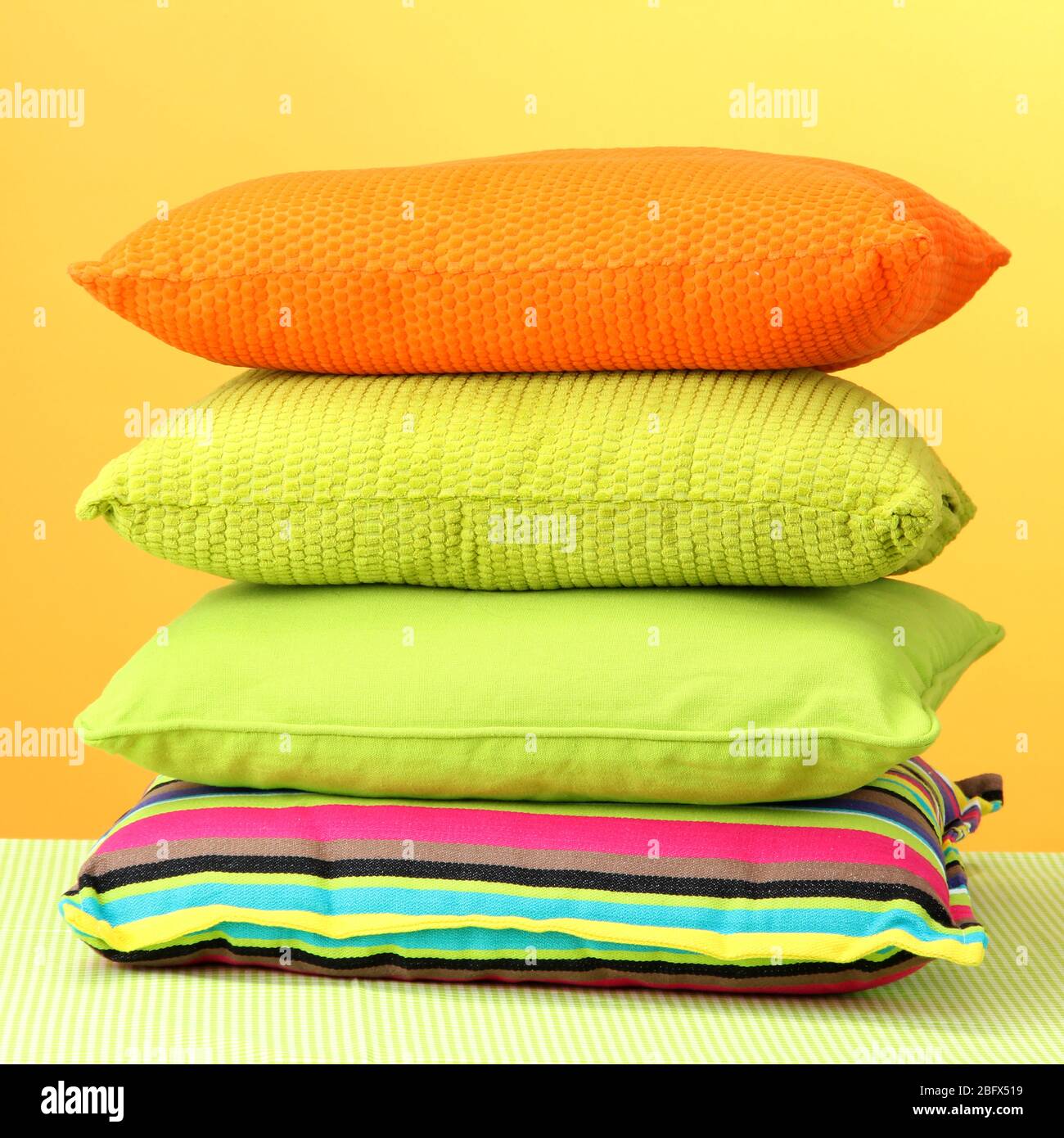 Colorful pillows on yellow background Stock Photo - Alamy