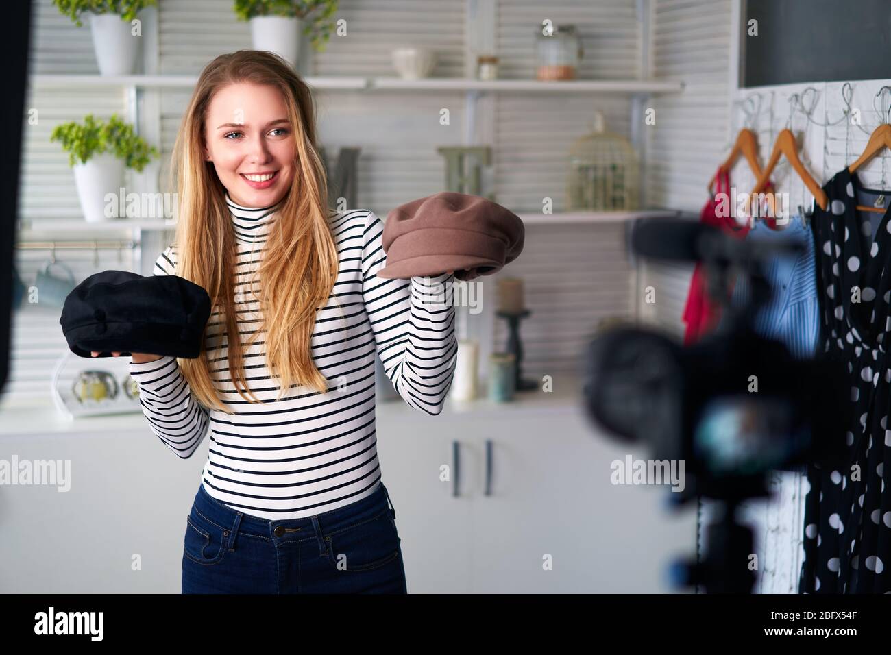 Fashion blogger woman in jeans and turtleneck showing fashionable caps ...