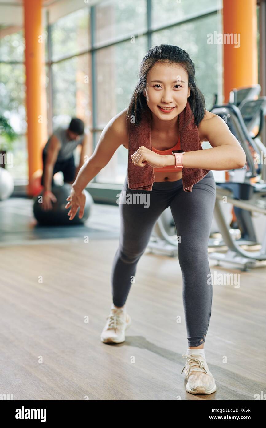 Smiling pretty young Asian woman leaning forward and moving leg back ...