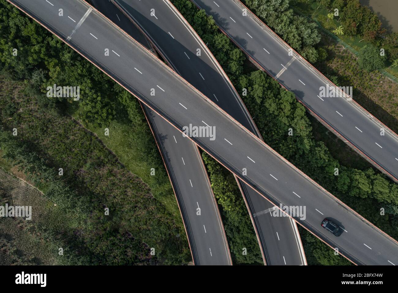 Aerial view of single car driving on highway and overpass Stock Photo ...