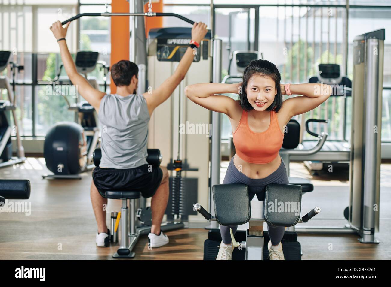 Cheerful young pretty Asian woman doing hypertension in gym when her ...