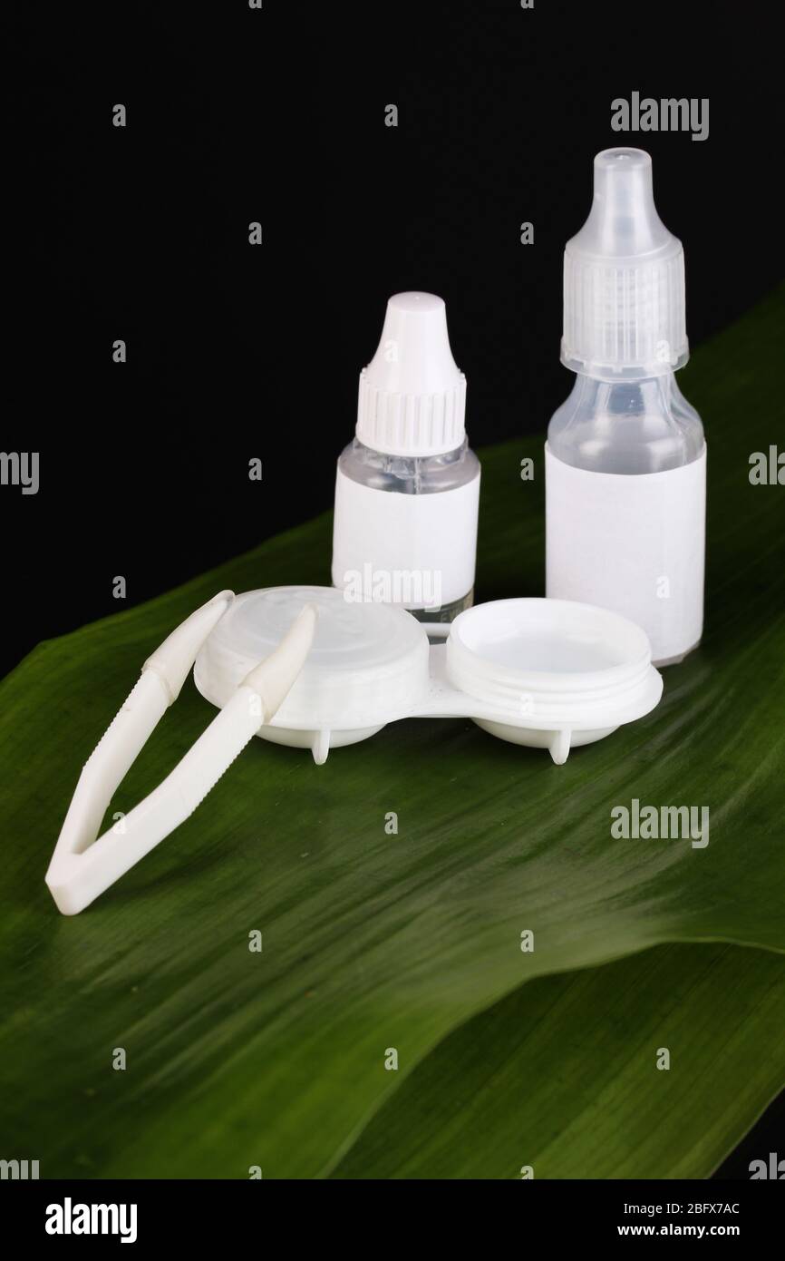 Eye drops and lenses on leaf on black background Stock Photo - Alamy