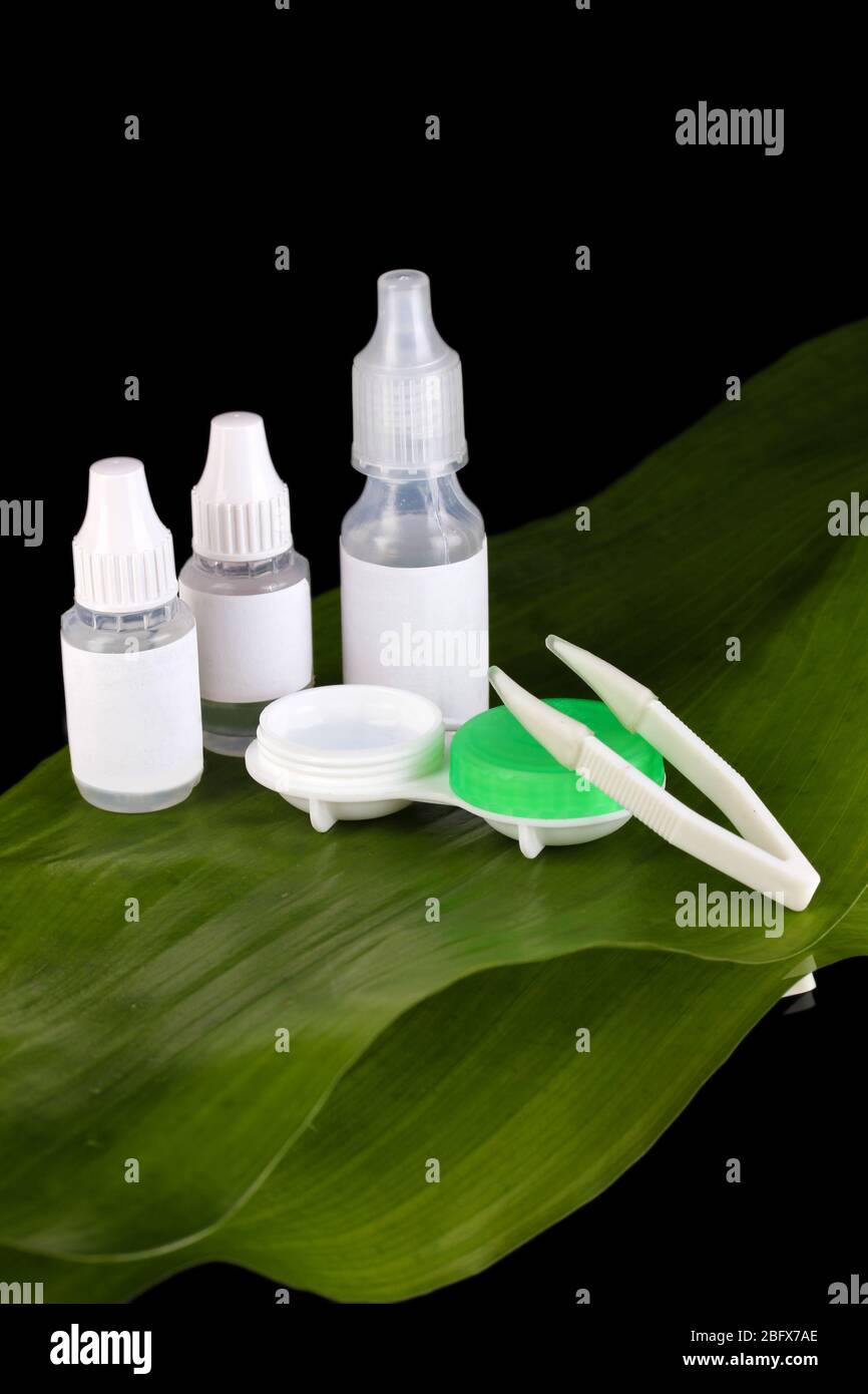 Eye drops and lenses on leaf on black background Stock Photo - Alamy