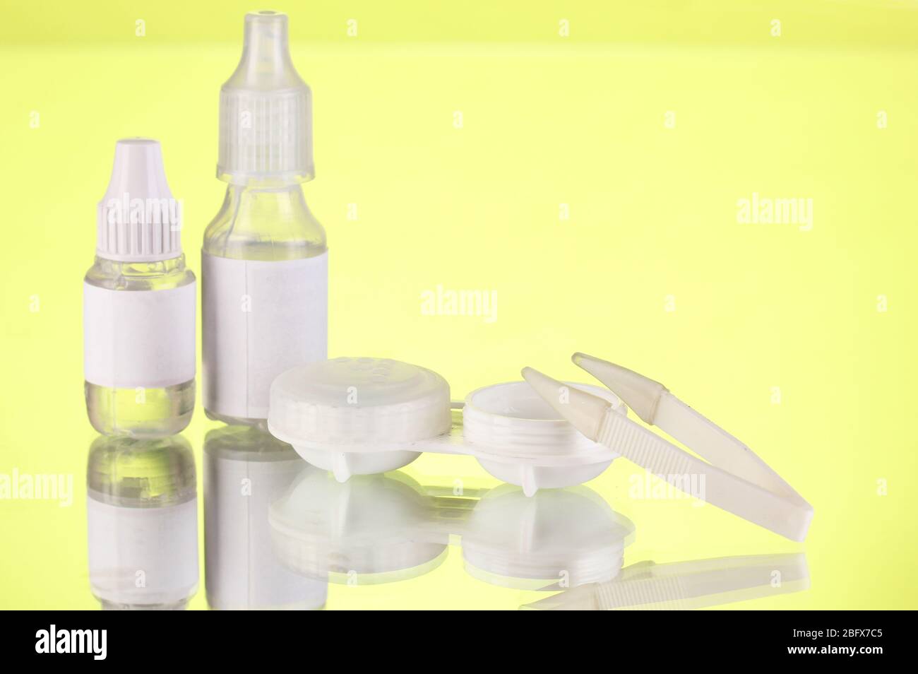 Eye drop and lenses on green background Stock Photo - Alamy