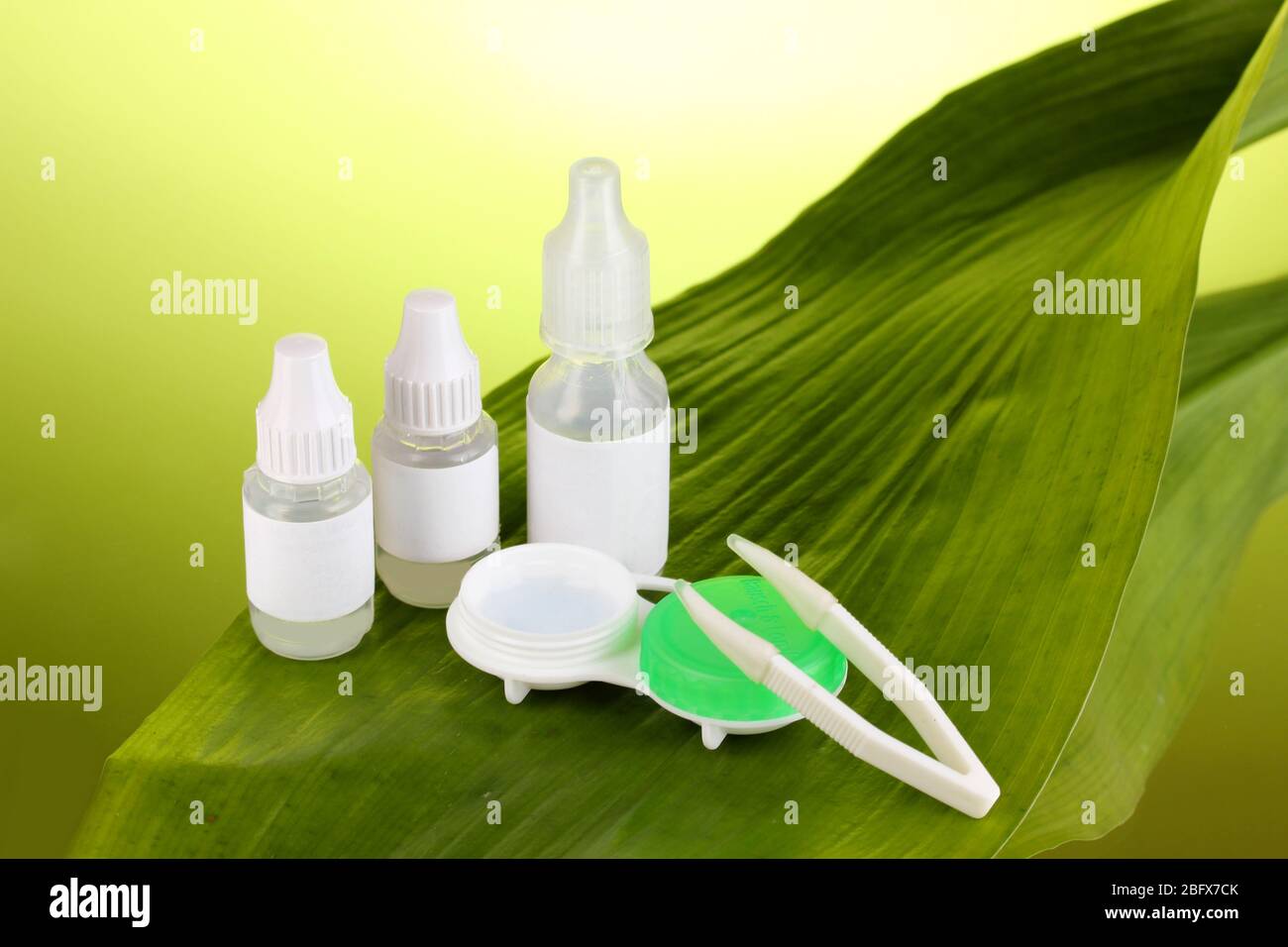 Eye drops and lenses on leaf on green background Stock Photo - Alamy