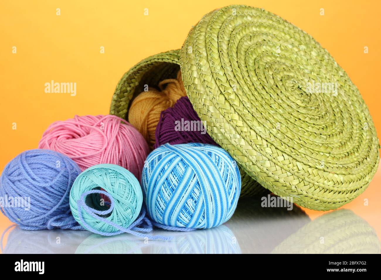 Colorful yarn for knitting in green basket on orange background Stock ...