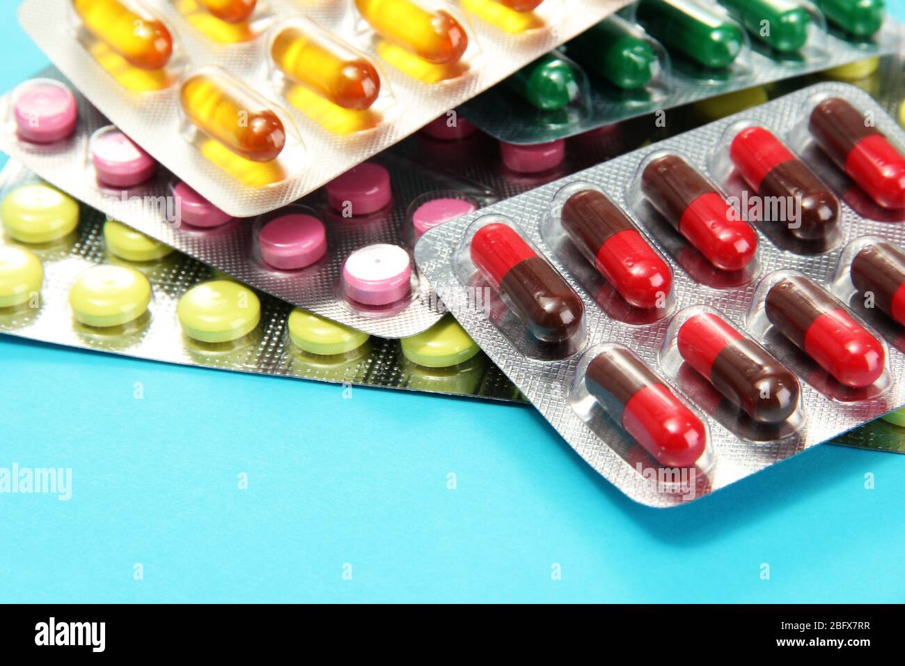 Capsules and pills packed in blisters, on blue background Stock Photo ...