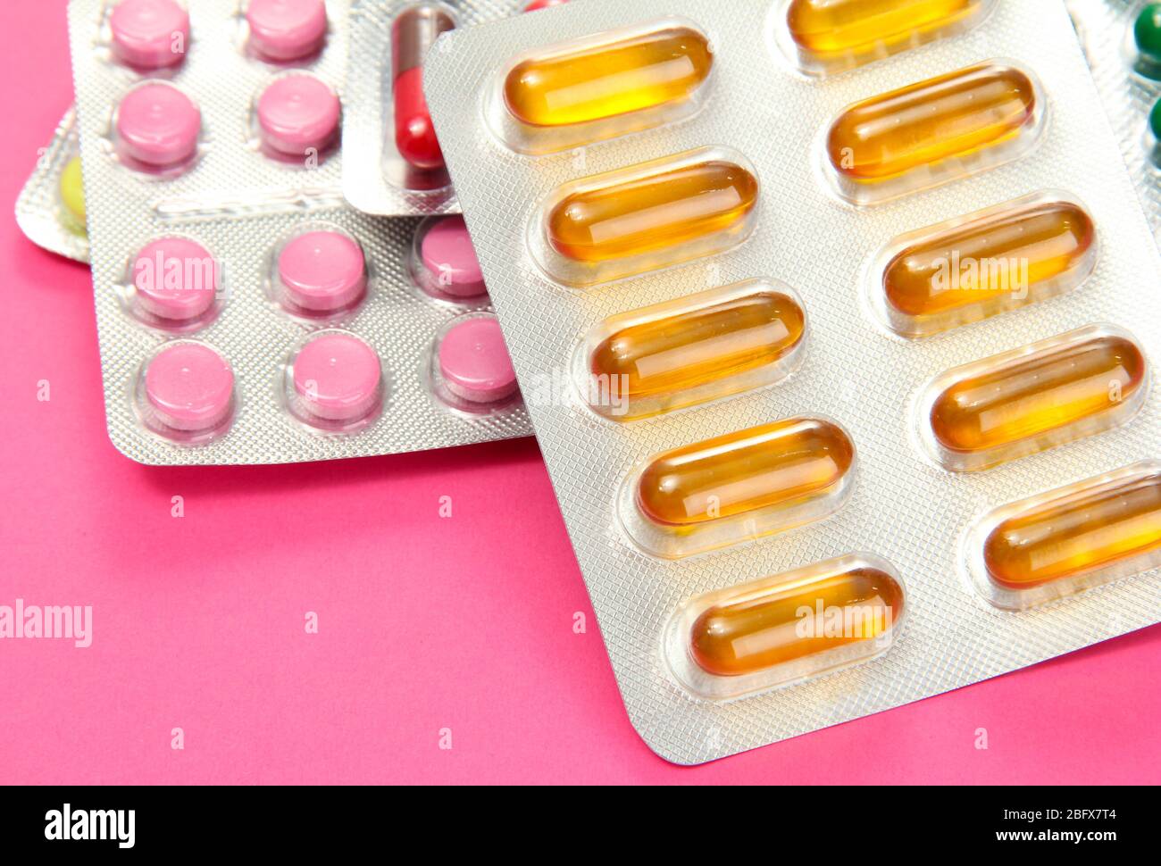 Capsules and pills packed in blisters, on pink background Stock Photo ...