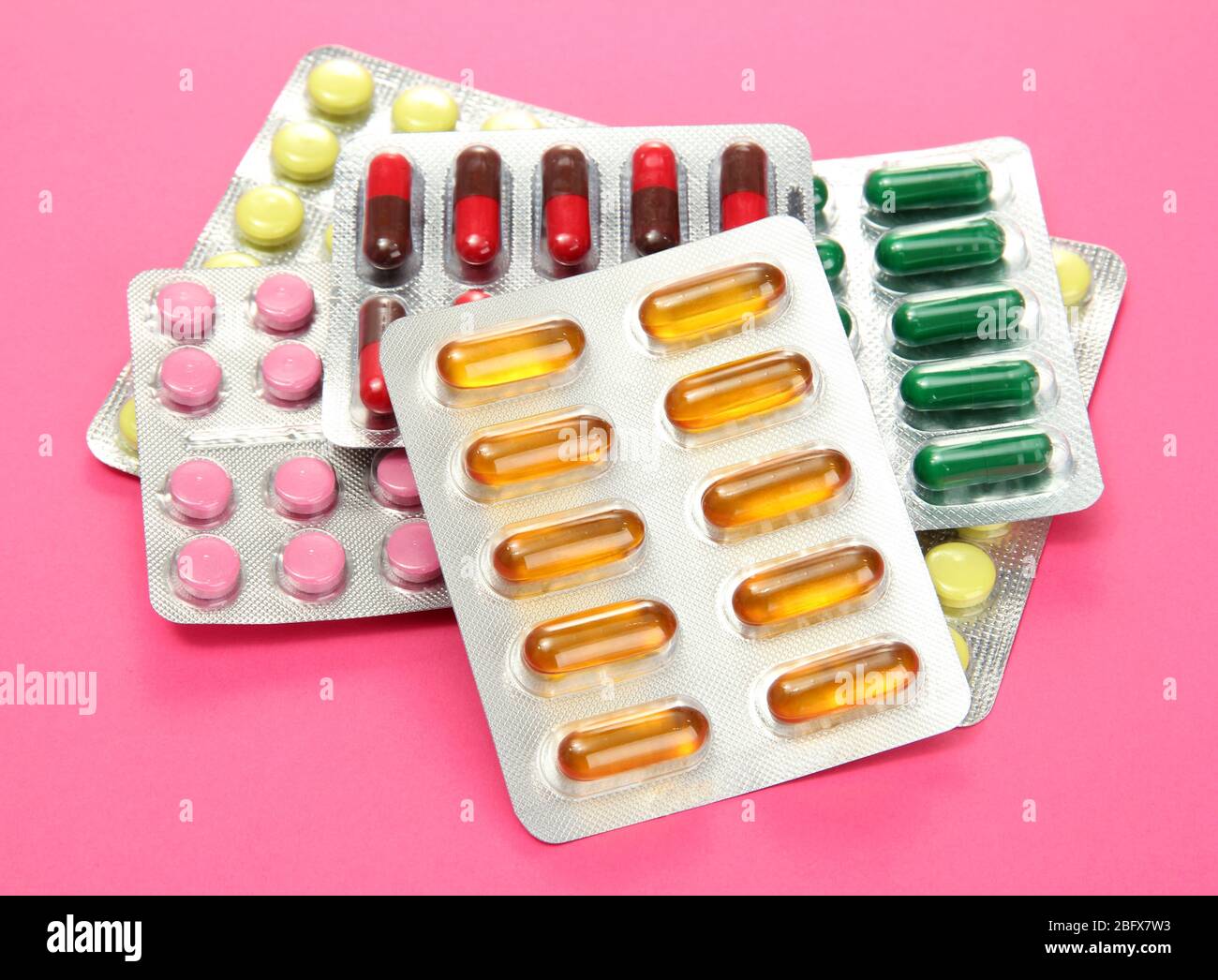 Capsules and pills packed in blisters, on pink background Stock Photo ...