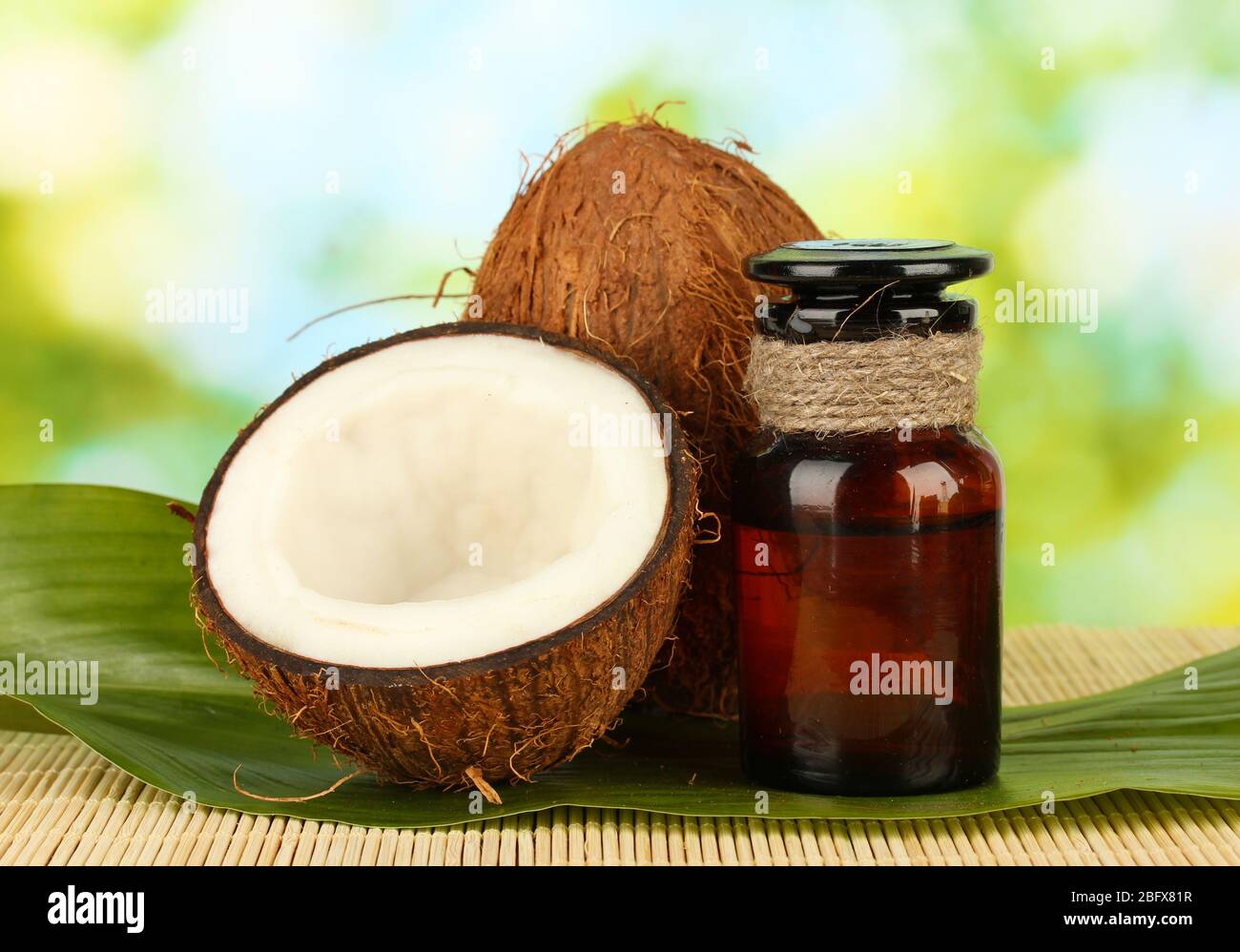 coconut oil in bottles with coconuts on green background Stock Photo ...