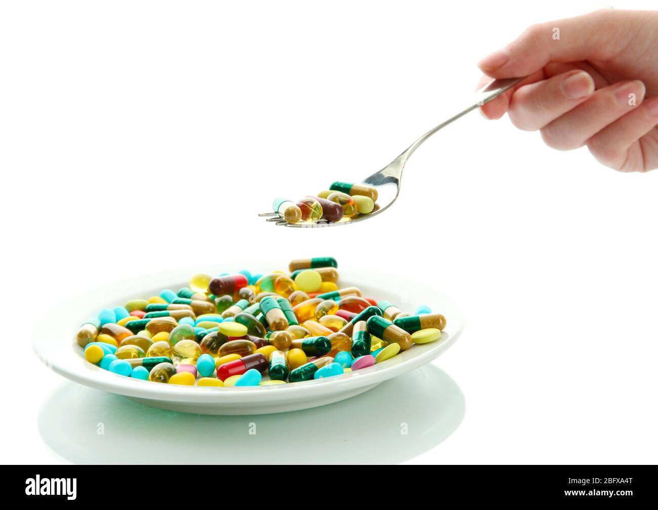 Colorful capsules and pills on plate with spoon in hand, close up Stock ...