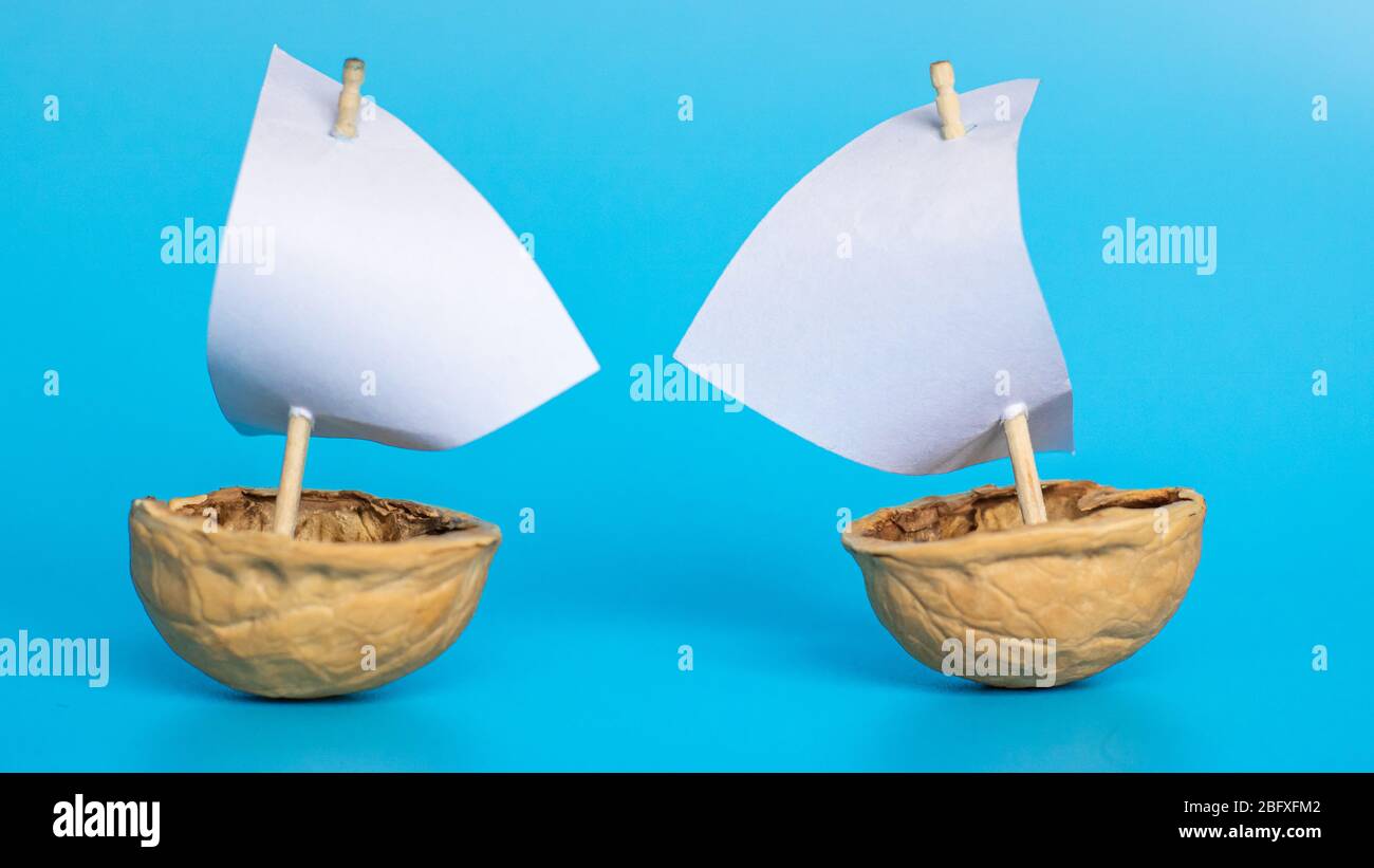 Two small boats made of nutshell with a white sail on the blue ...