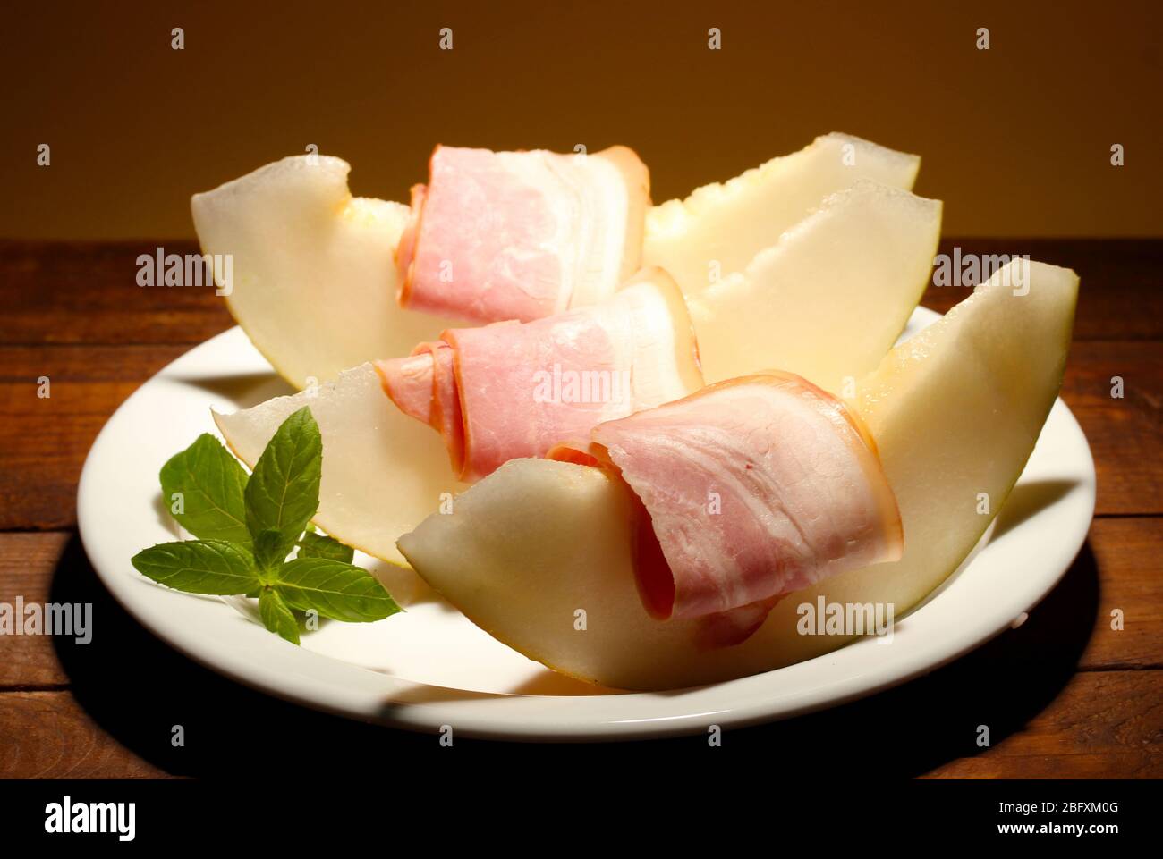 parma ham and melon, on wooden table, on yellow background Stock Photo ...